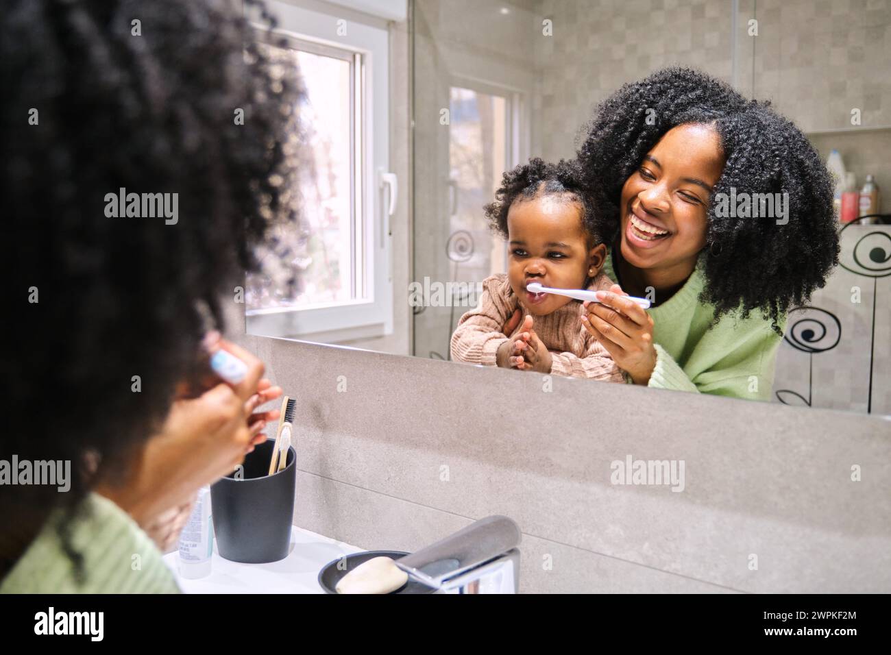 Cuban mother brushing her toddler daughter's teeth and laughing Stock ...