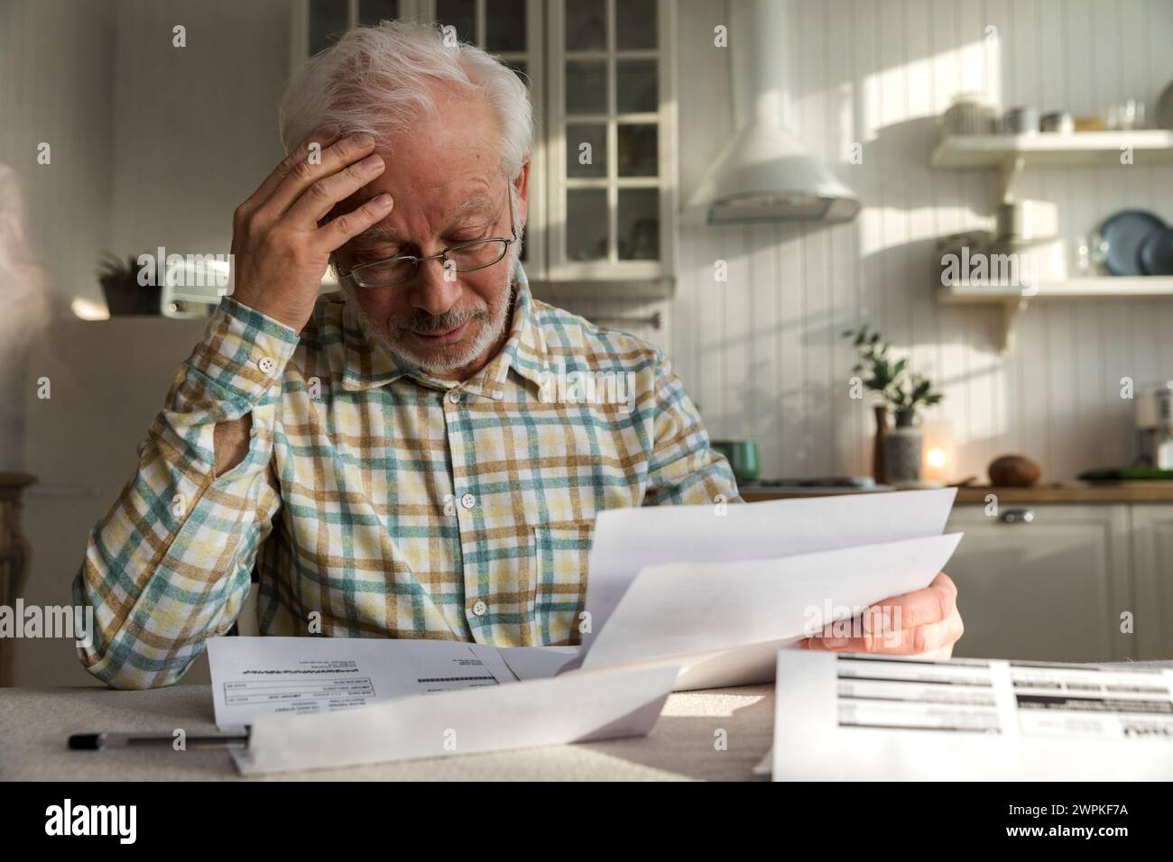confused elderly man sitting with bills and taxes in kitchen Stock ...