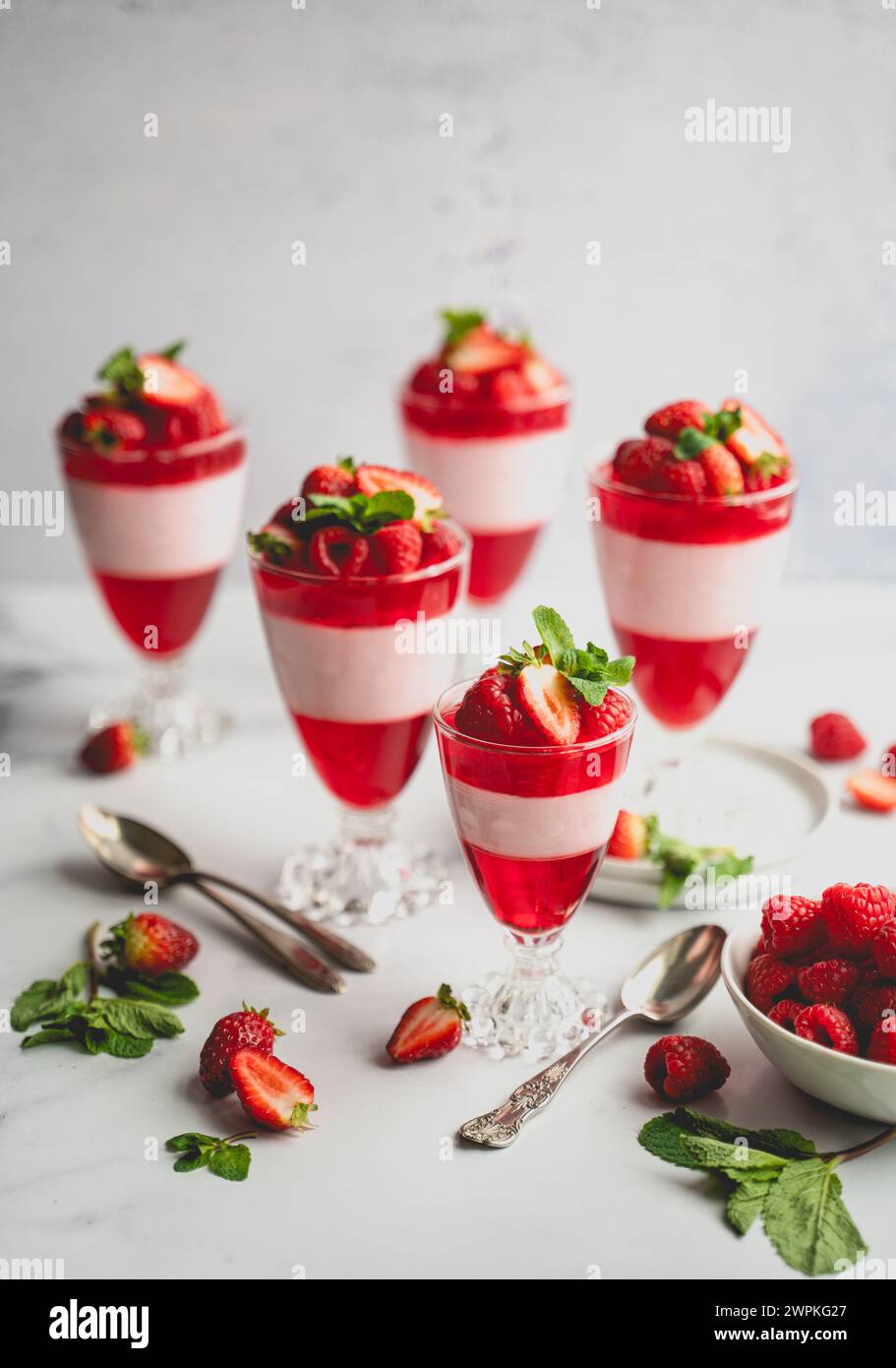 Layered berry, jelly and mousse parfait desserts on white background ...