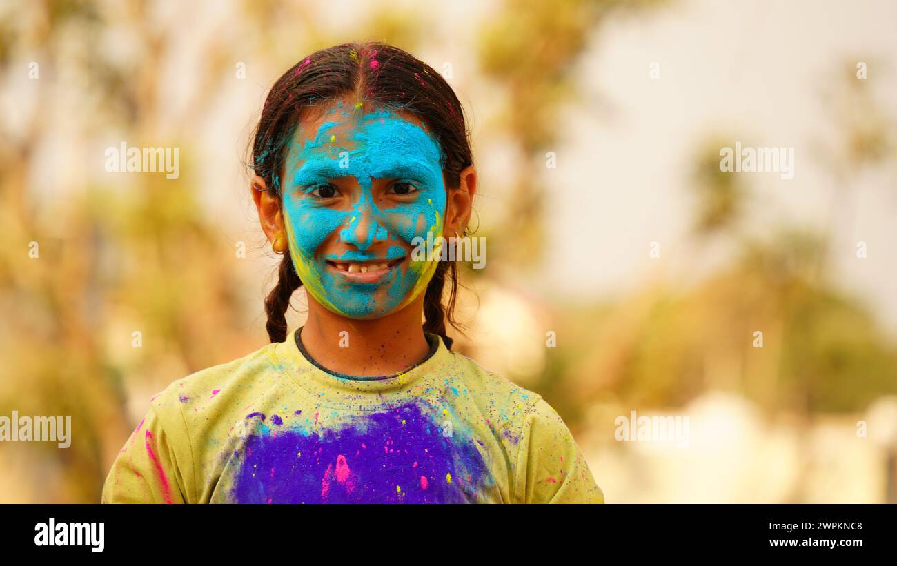 Happy Indian friends or kids celebrating the Hindu festival of Holi by applying colors to each ...