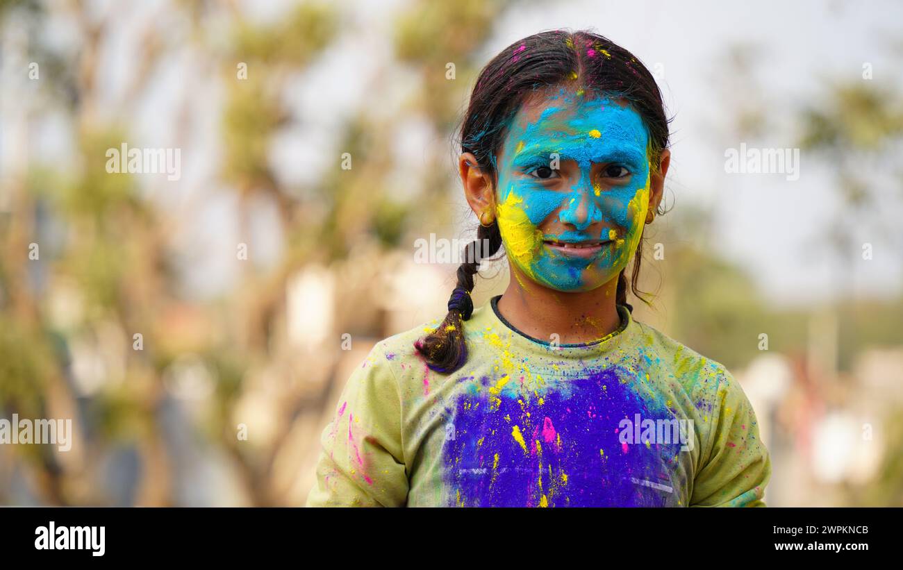 Young cute cheerful little girl kid with applied holi colors powder ...