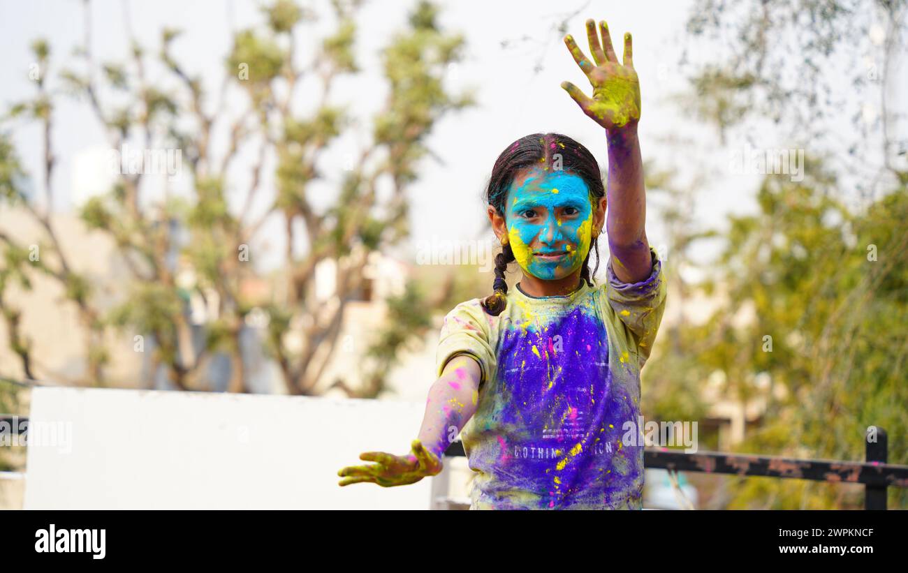 Young cute cheerful little girl kid with applied holi colors powder ...