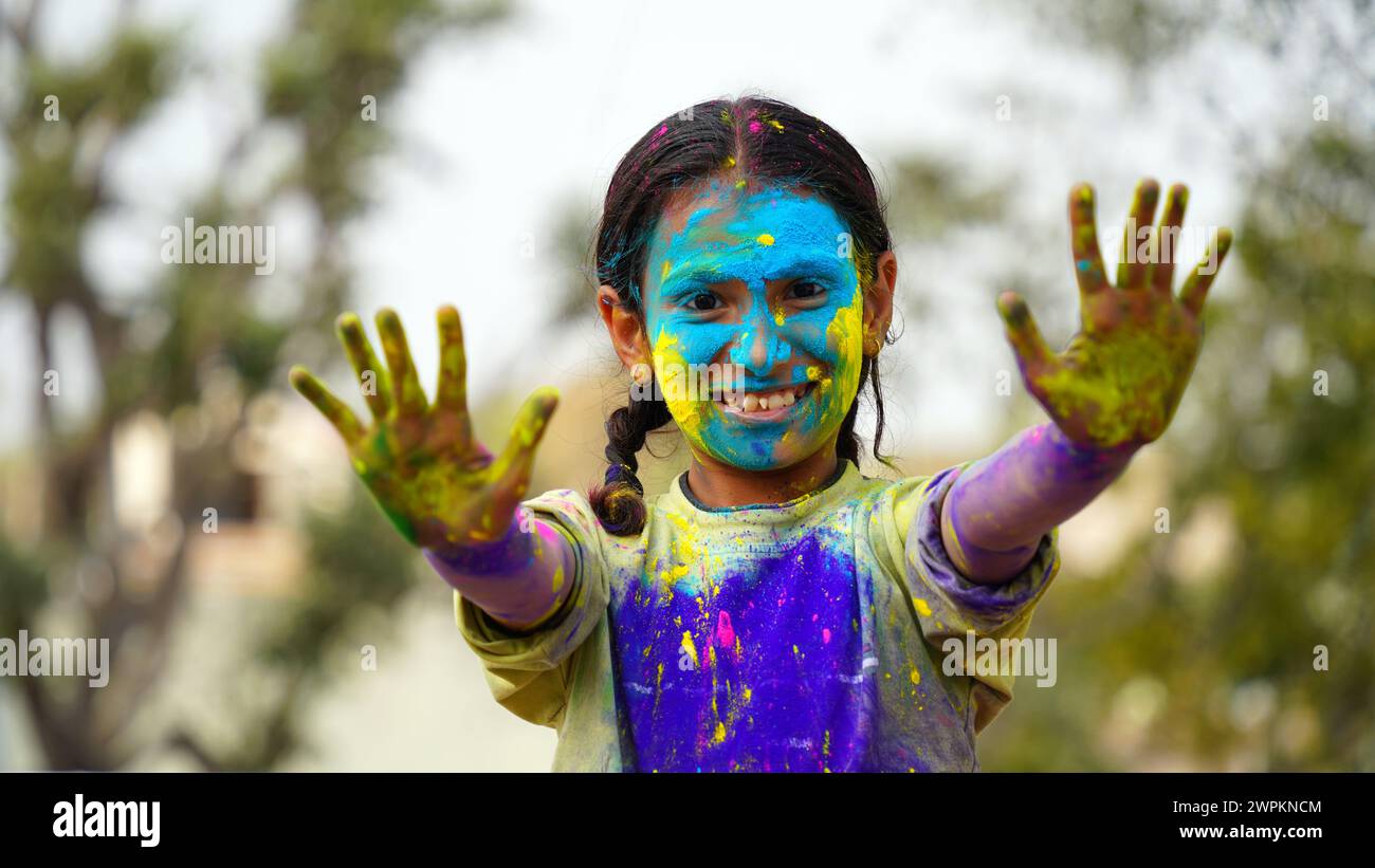 Young cute cheerful little girl kid with applied holi colors powder ...