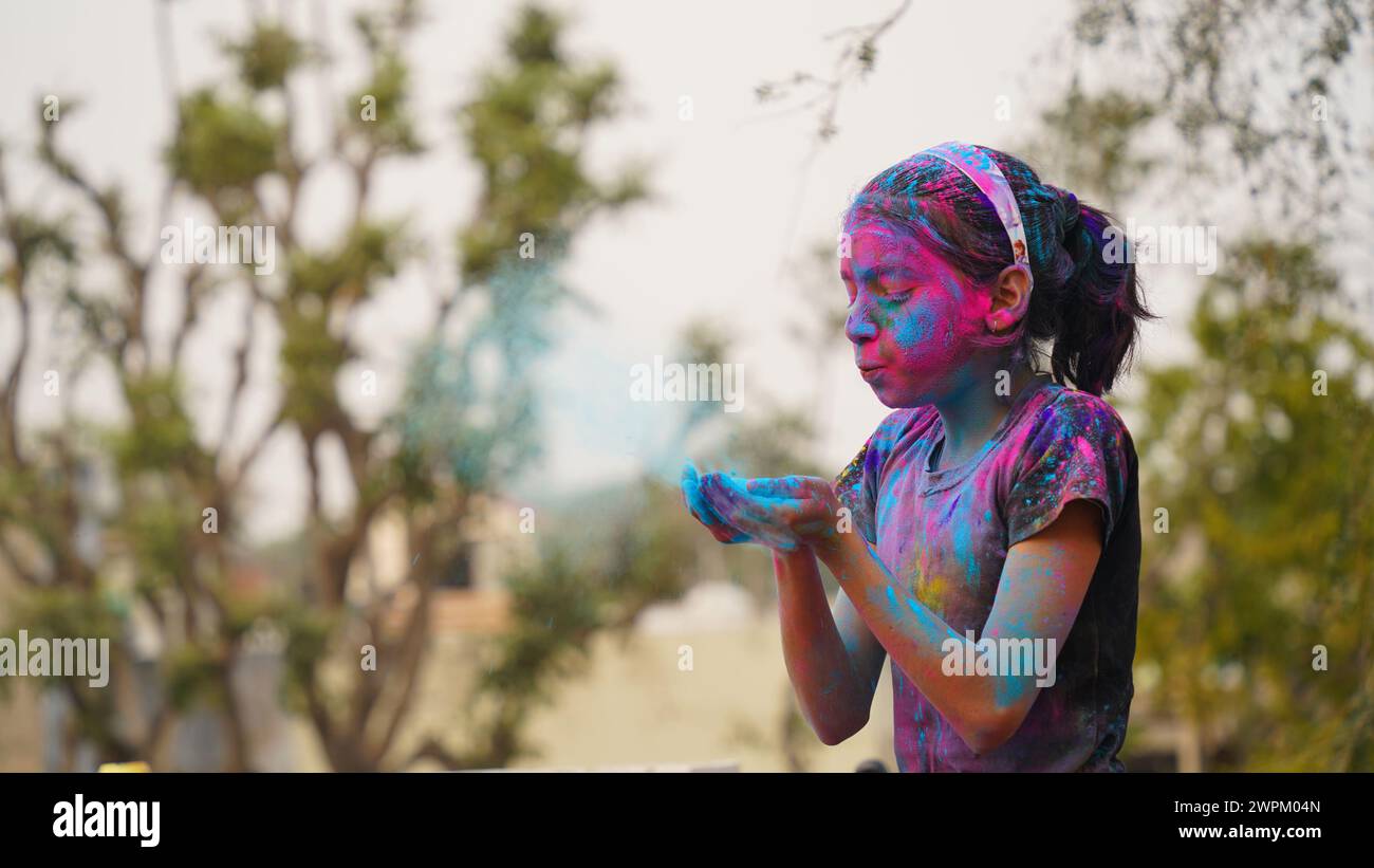 Young cute cheerful little girl kid with applied holi colors powder ...