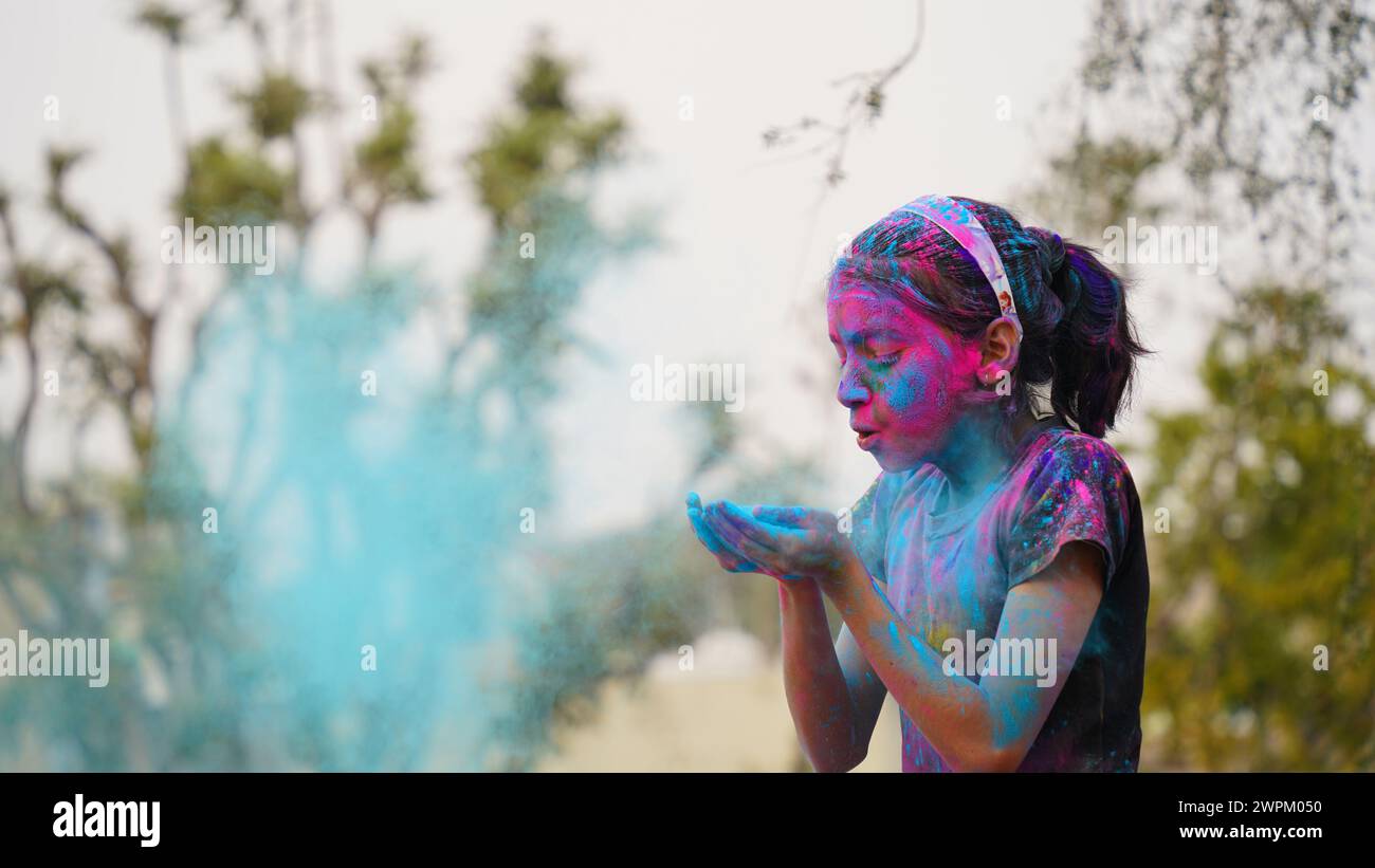 Young cute cheerful little girl kid with applied holi colors powder ...