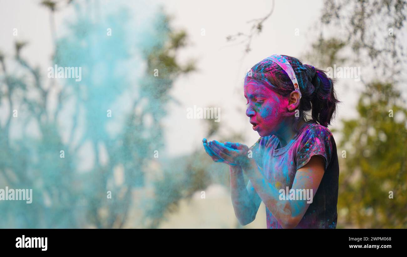 Happy Indian friends or kids celebrating the Hindu festival of Holi by applying colors to each ...