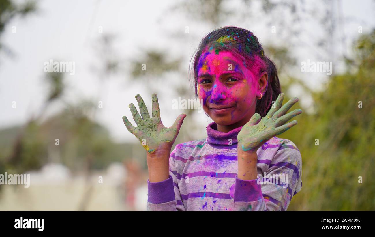 Happy Indian friends or kids celebrating the Hindu festival of Holi by applying colors to each ...
