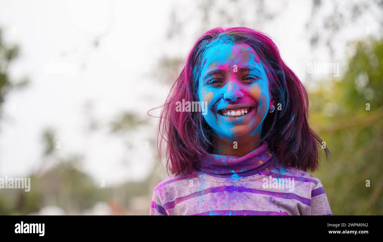 Happy Indian friends or kids celebrating the Hindu festival of Holi by applying colors to each ...