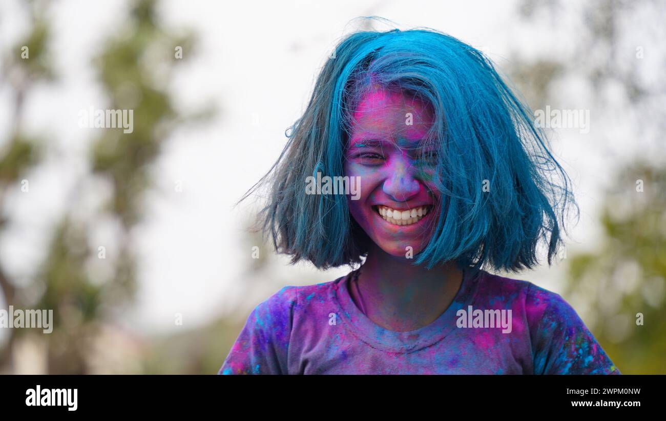 Happy Indian friends or kids celebrating the Hindu festival of Holi by applying colors to each ...