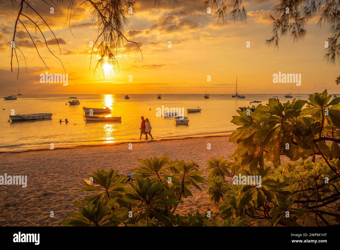 View of boats and people on Mon Choisy Public Beach at sunset ...