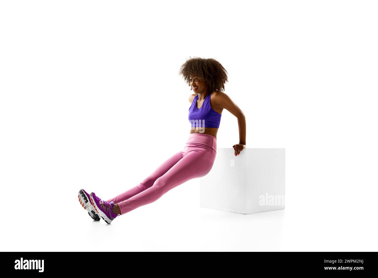 Fit African-American woman in purple sportswear performing triceps dips ...