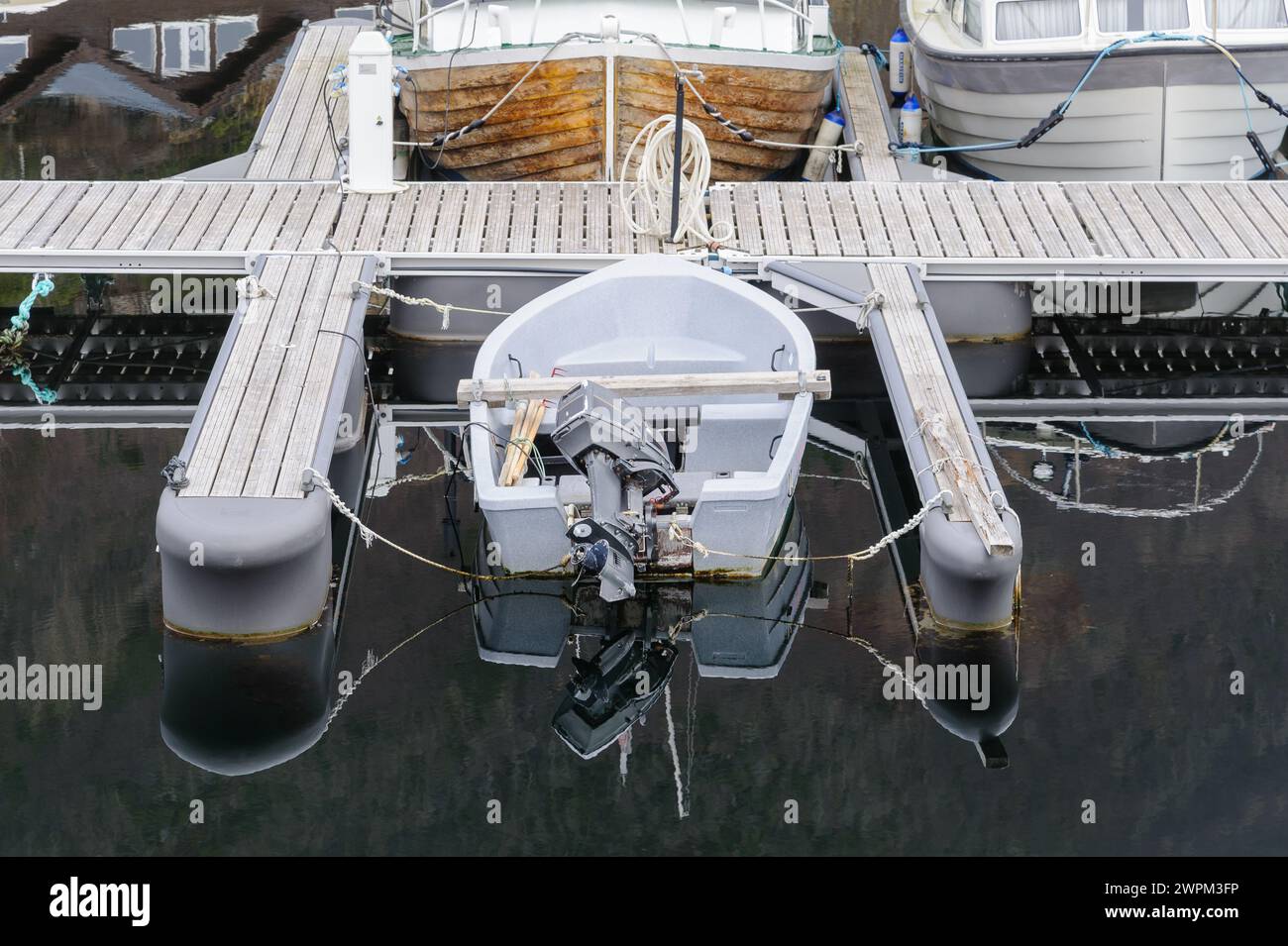 A top-down view of a single motorboat tied to a serene, empty dock ...
