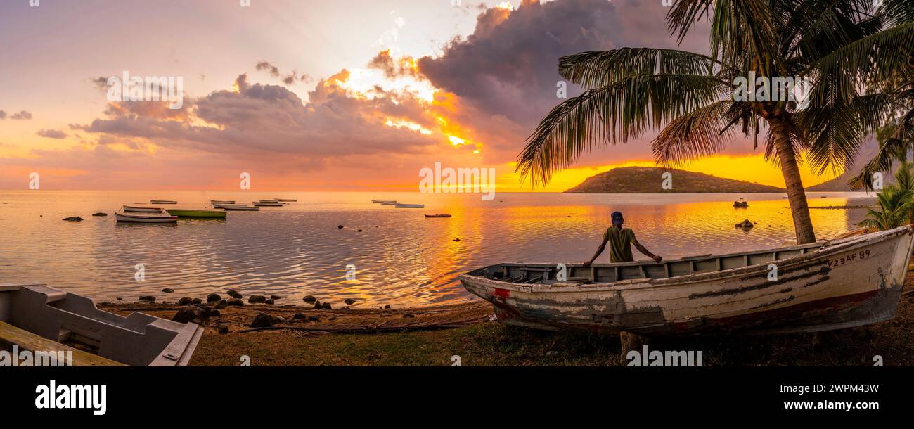 View of local man sat on boat viewing Le Morne from Le Morne Brabant at ...