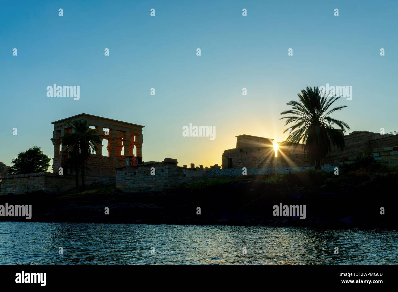 View of the ancient Philae temple from the Nile river at sunset in ...