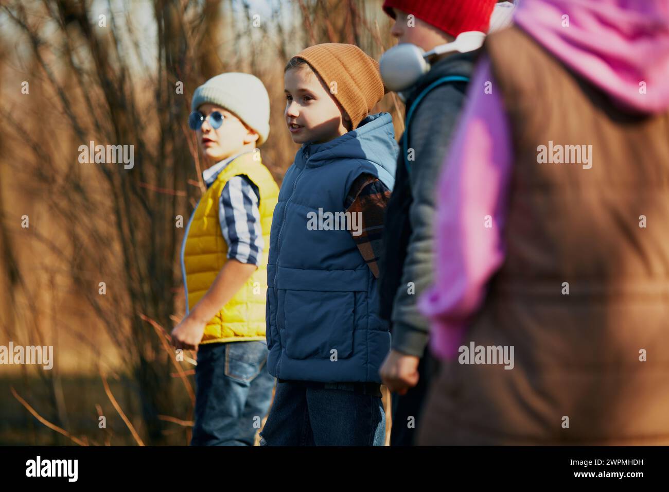 Curious kids, classmates, in warm attire observing something ...