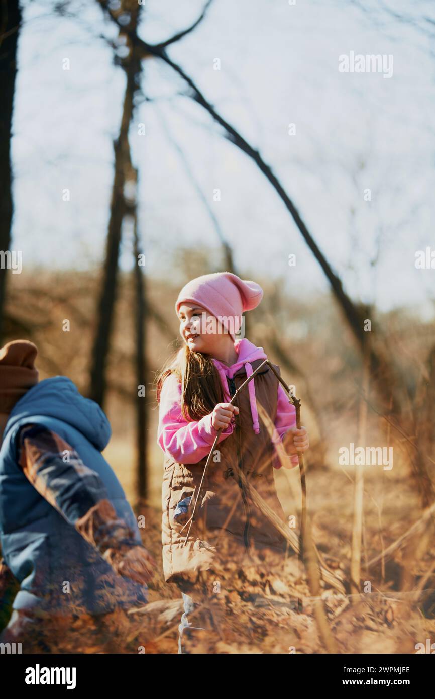Little children, in warm jacket and cap finding joy in simple stick ...