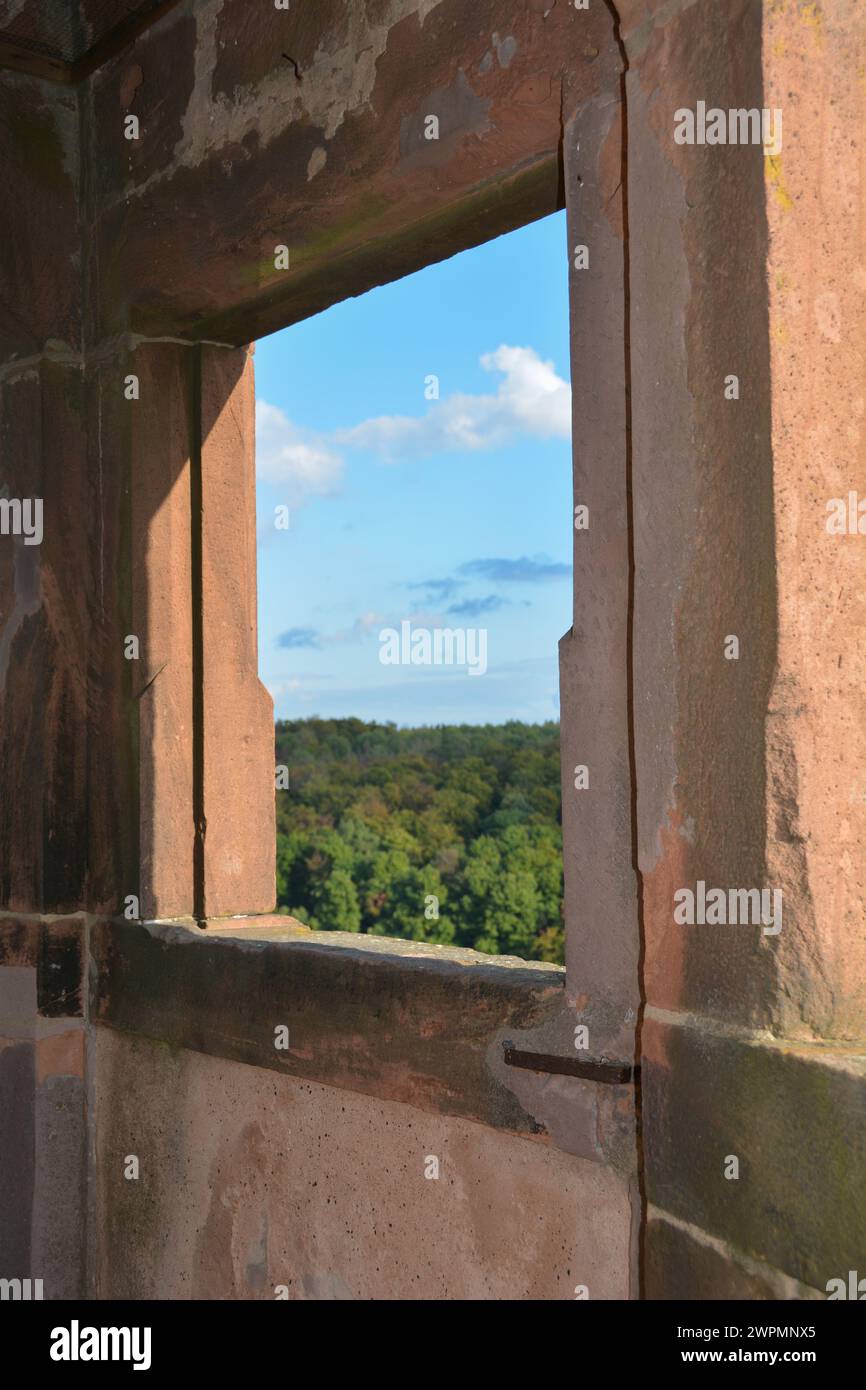 View through an old castle window on a blue sky with white clouds and ...