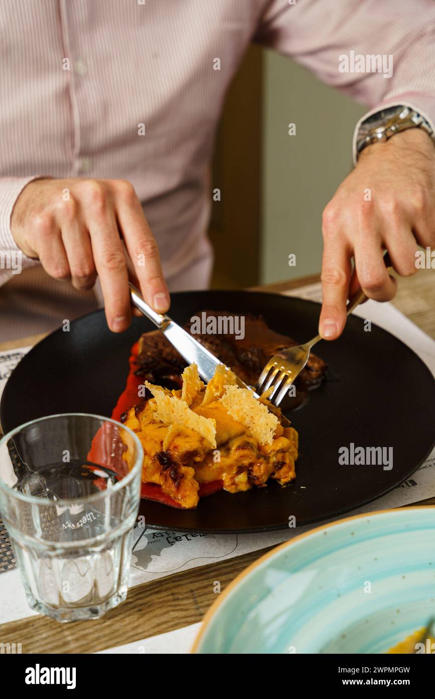 Man eating mac and cheese and slices of meat Stock Photo - Alamy