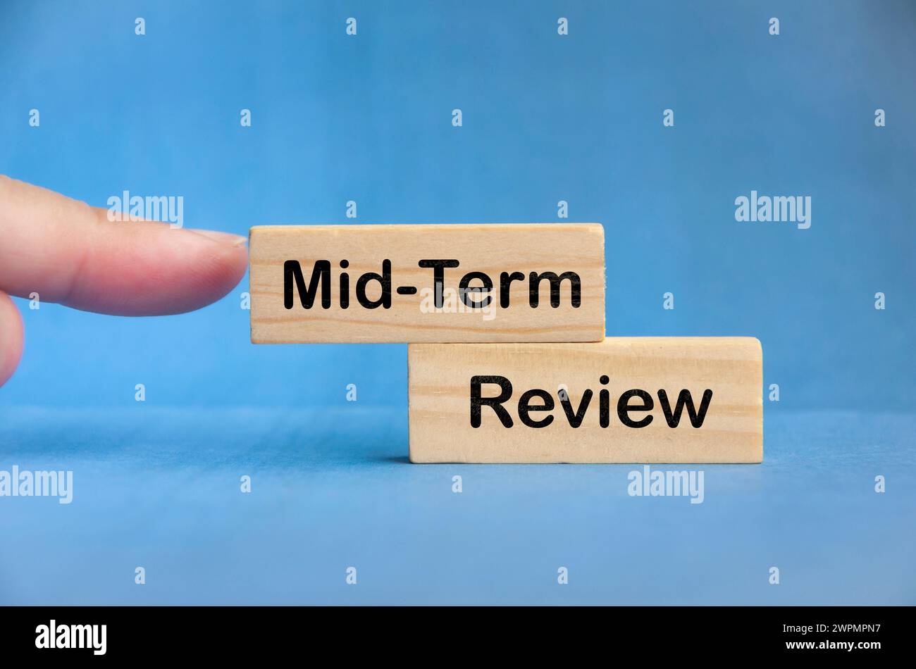 Finger pointing Mid Term Review text on wooden block with blue ...