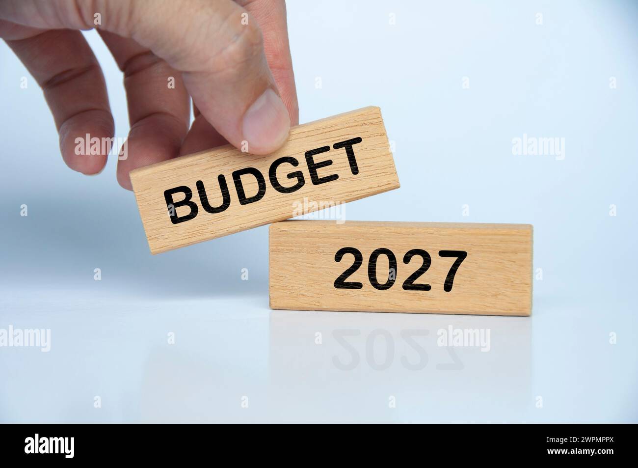 Hand holding wooden block with Budget 2027 text on white background ...