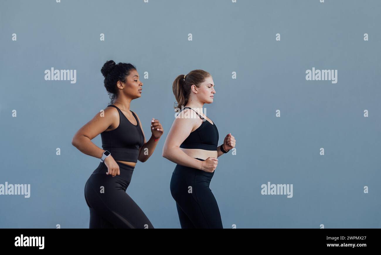 Side view of two females with similar body types running together at ...