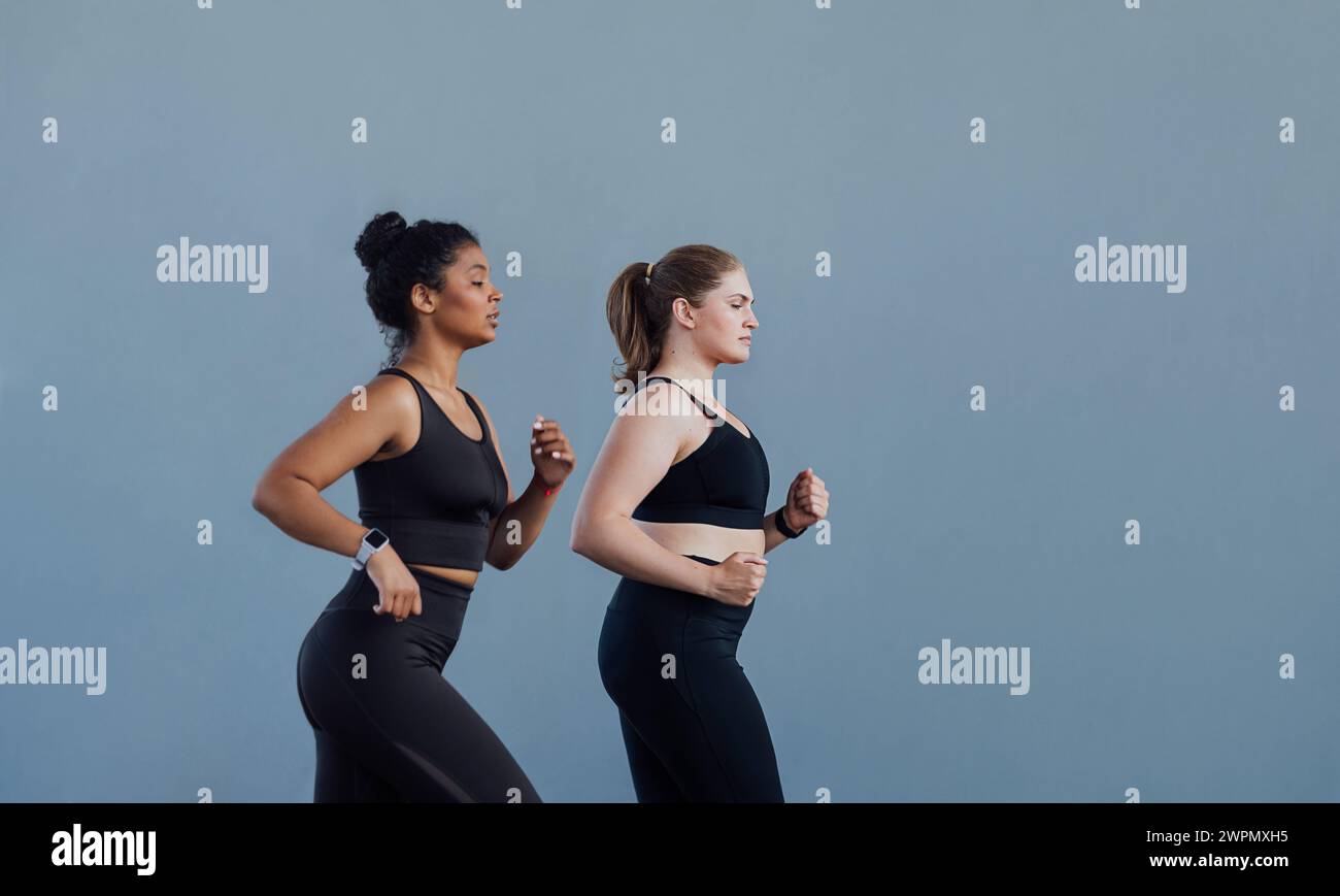 Side view of two females with similar body types running together at ...