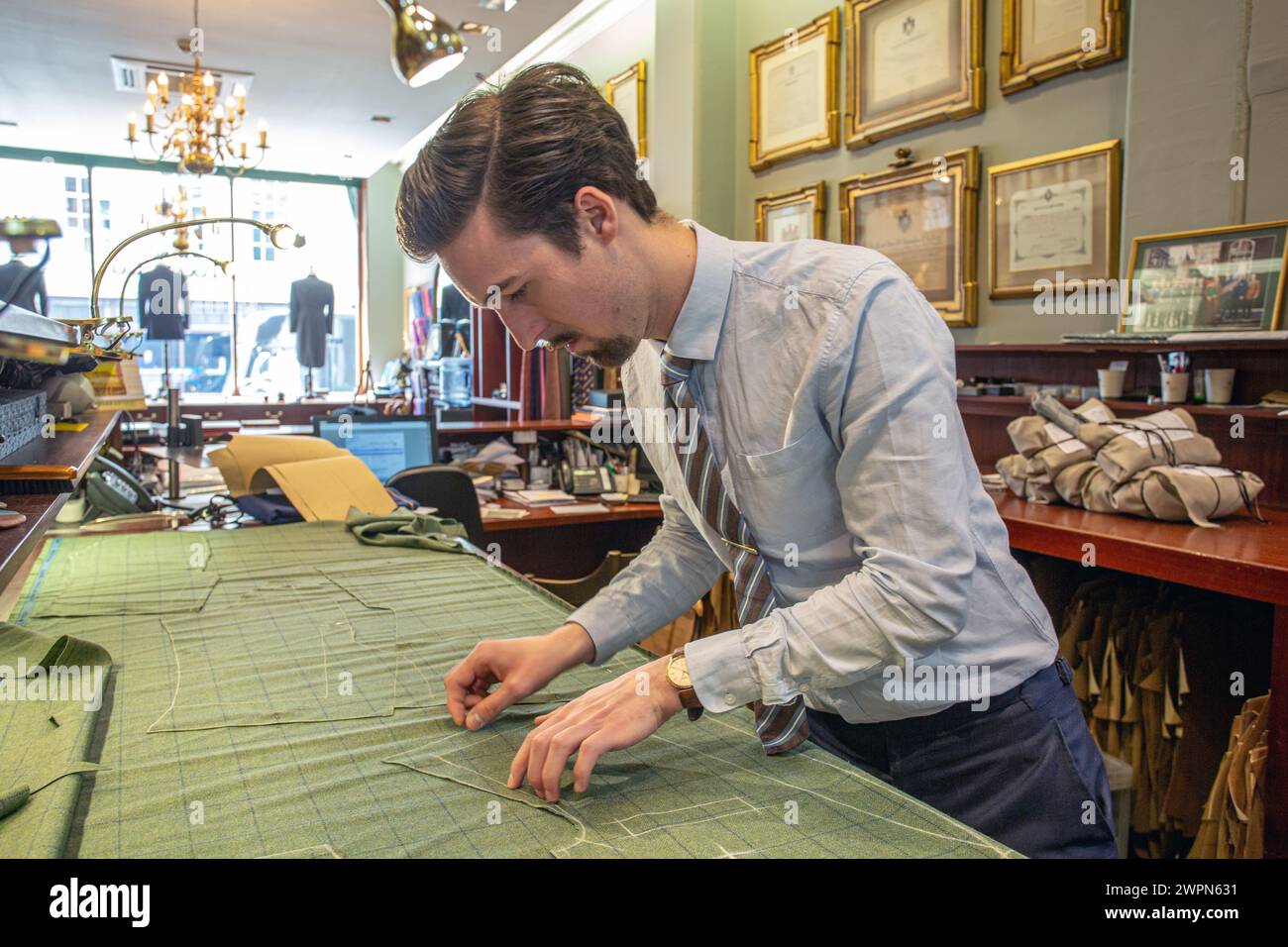 Young tailor marking cloth in Henry Pole bespoke tailor at ,Savile Row ...