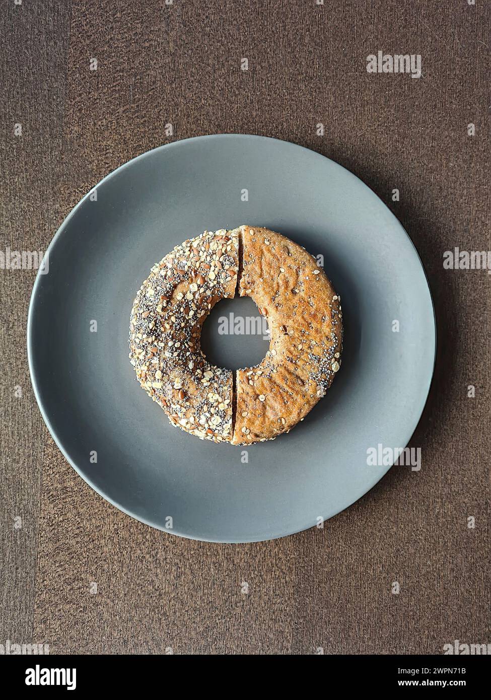 A bagel is cut in half with the underside and the top side with seeds ...