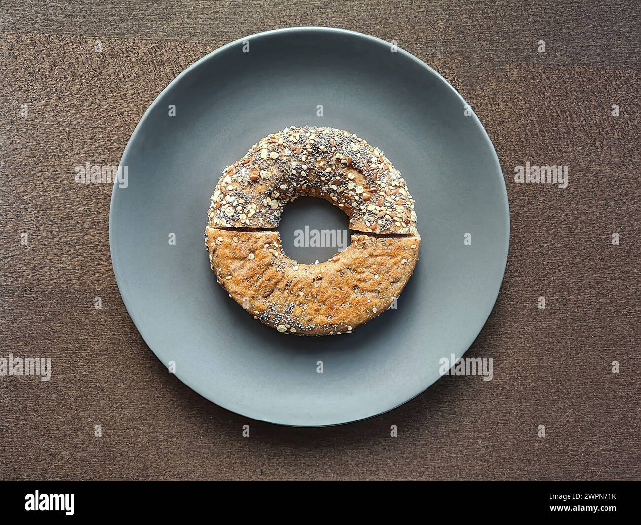A bagel is cut in half with the underside and the top side with seeds ...