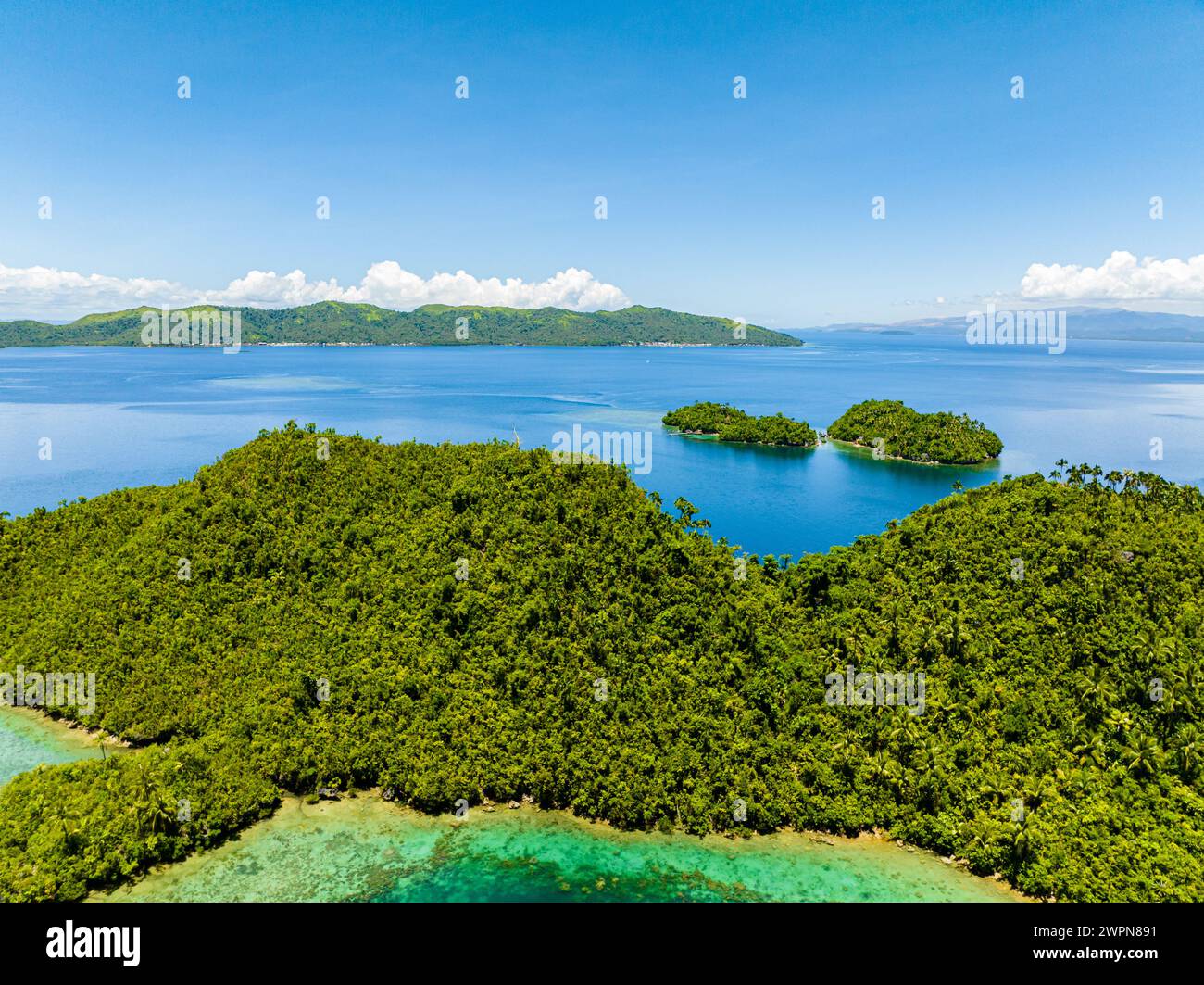 Tropical Island in open sea surface and blue sky and clouds. Mindanao ...