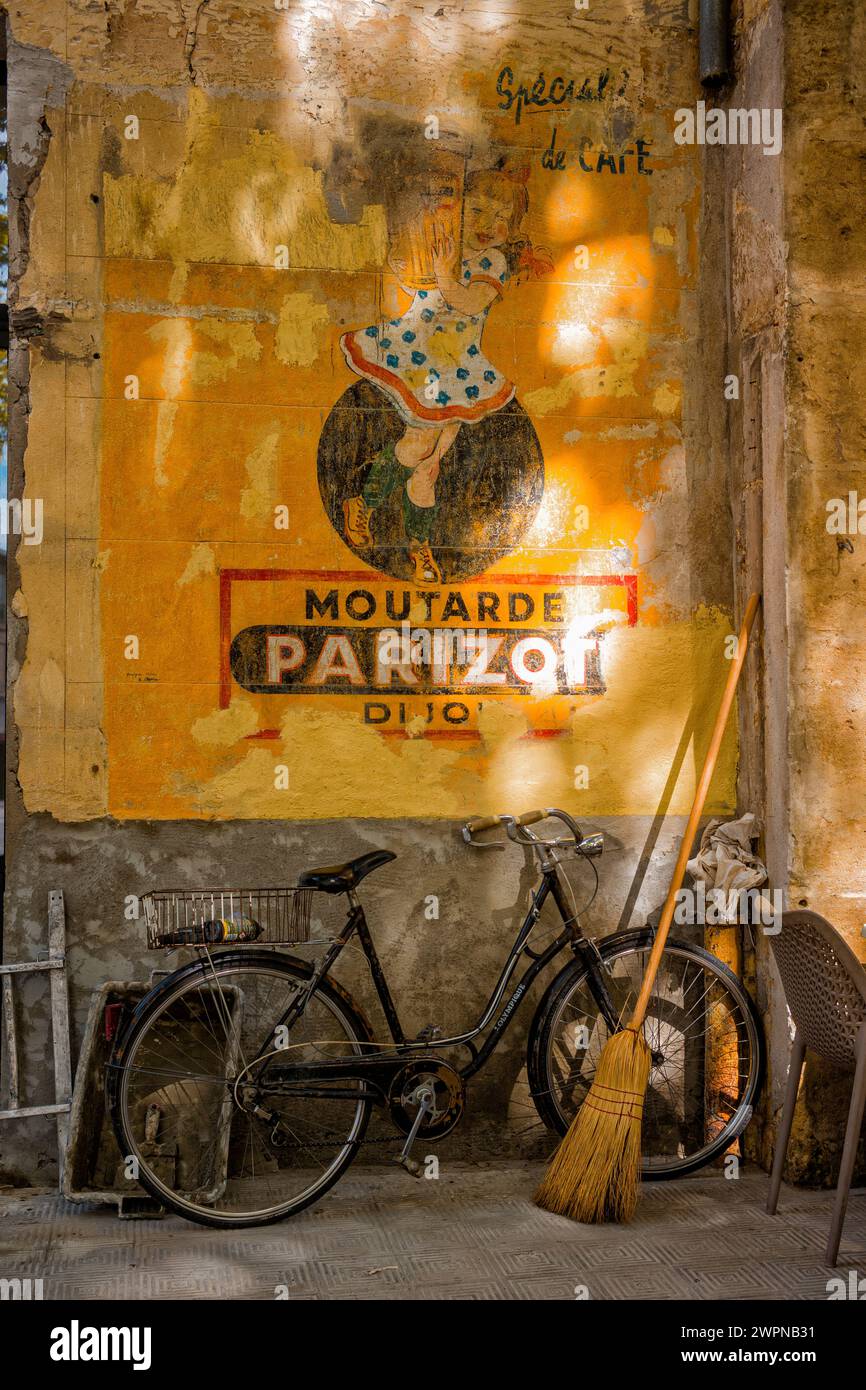 Bicycle and broom in front of historical advertising in arles hi-res ...