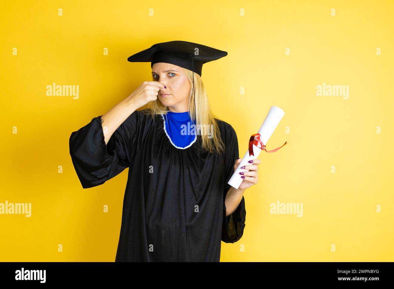 Beautiful blonde young woman wearing graduation cap and ceremony robe ...