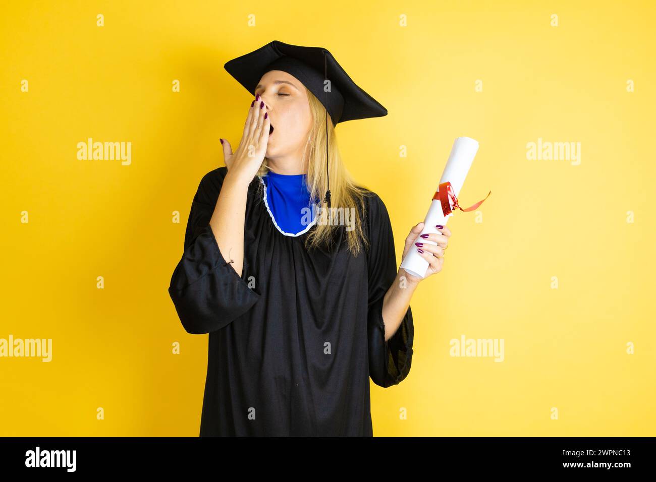 Beautiful blonde young woman wearing graduation cap and ceremony robe ...