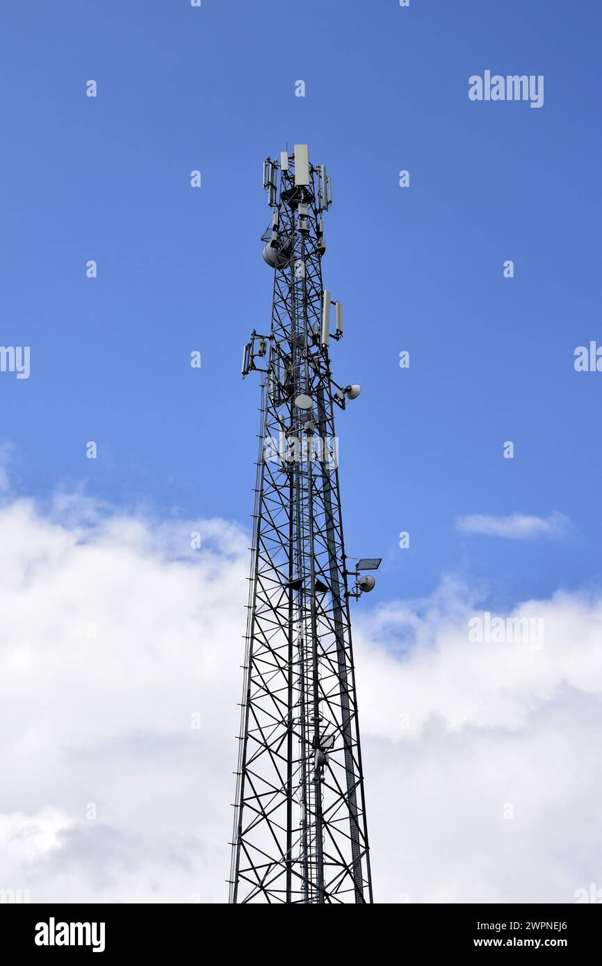 Cell tower against blue sky with clouds. A cell site or tower with antennae and ...