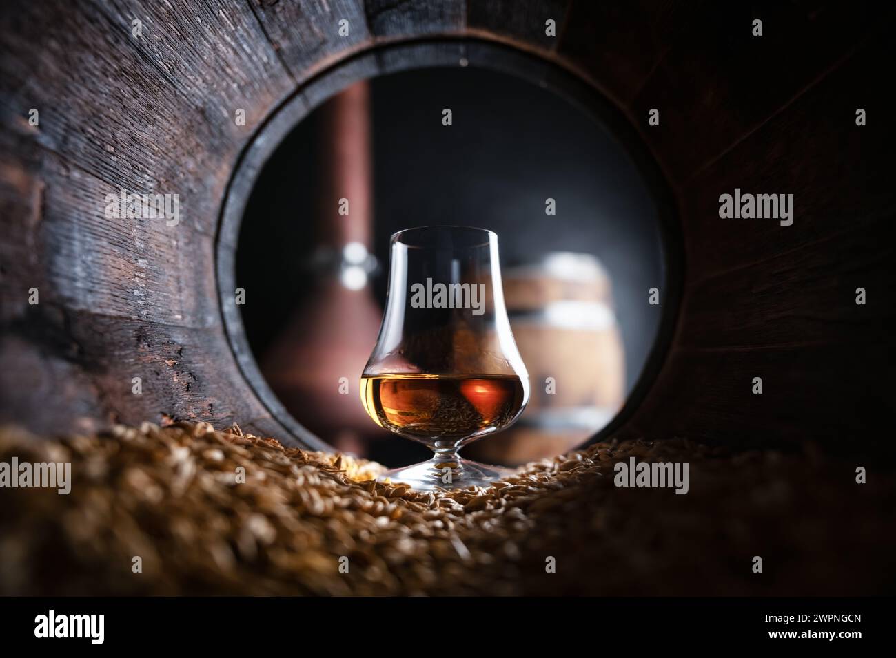 A glass of bourbon whiskey in old oak barrel. Copper alambic and oak ...