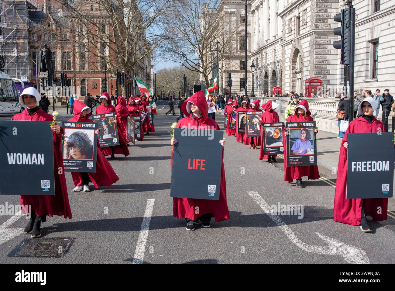 London, UK. 08th Mar, 2024. Protesters hold placards and white roses ...