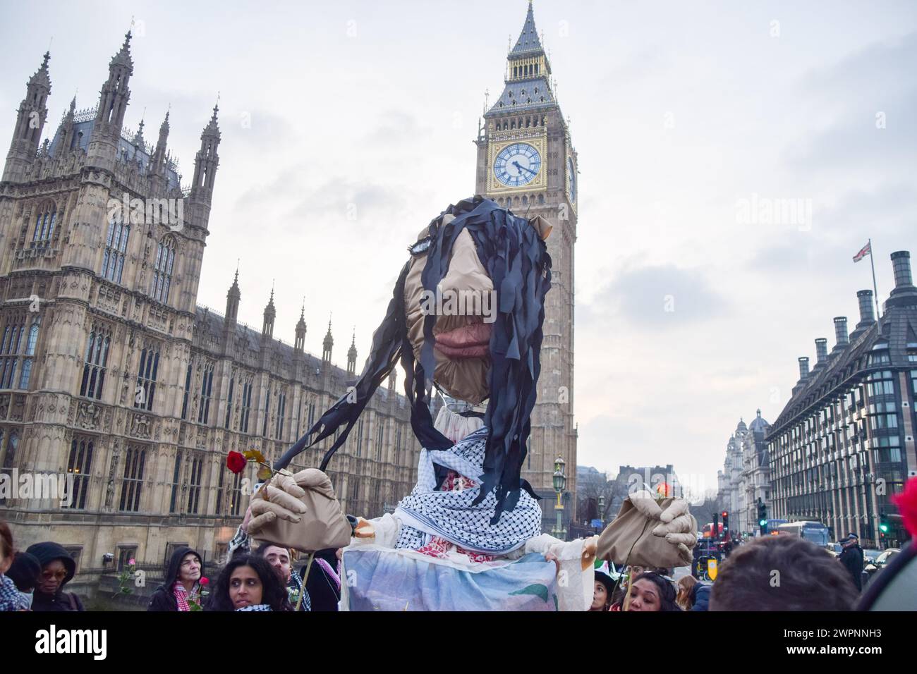 London, UK. 8th March 2024. Pro-Palestine protesters carry a giant ...