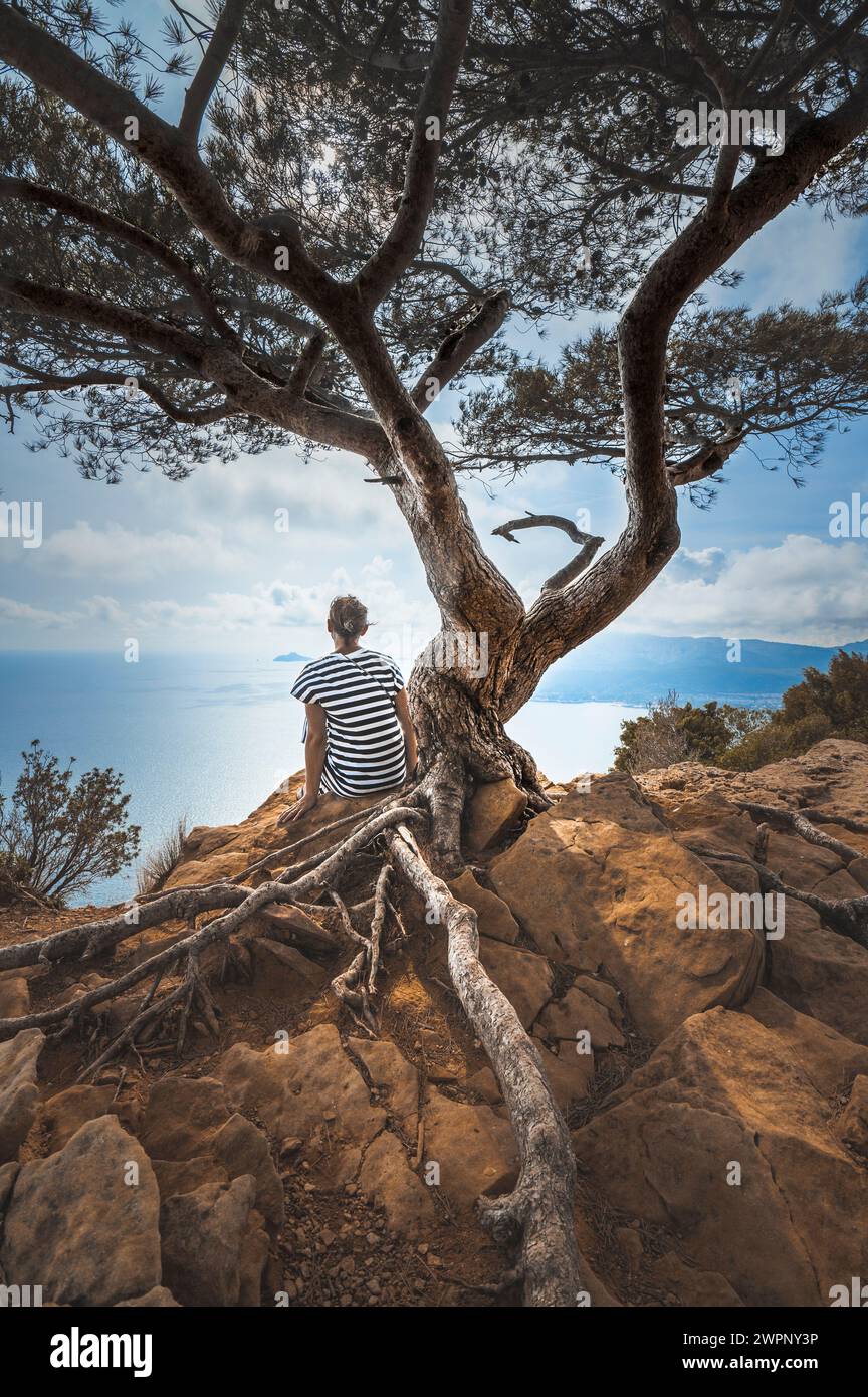 Woman sitting on rocks by sea hi-res stock photography and images - Alamy