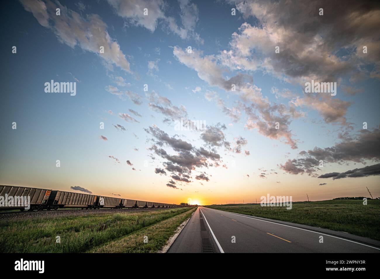A beautiful setting sun at the end of a Nebraska highway and railroad ...