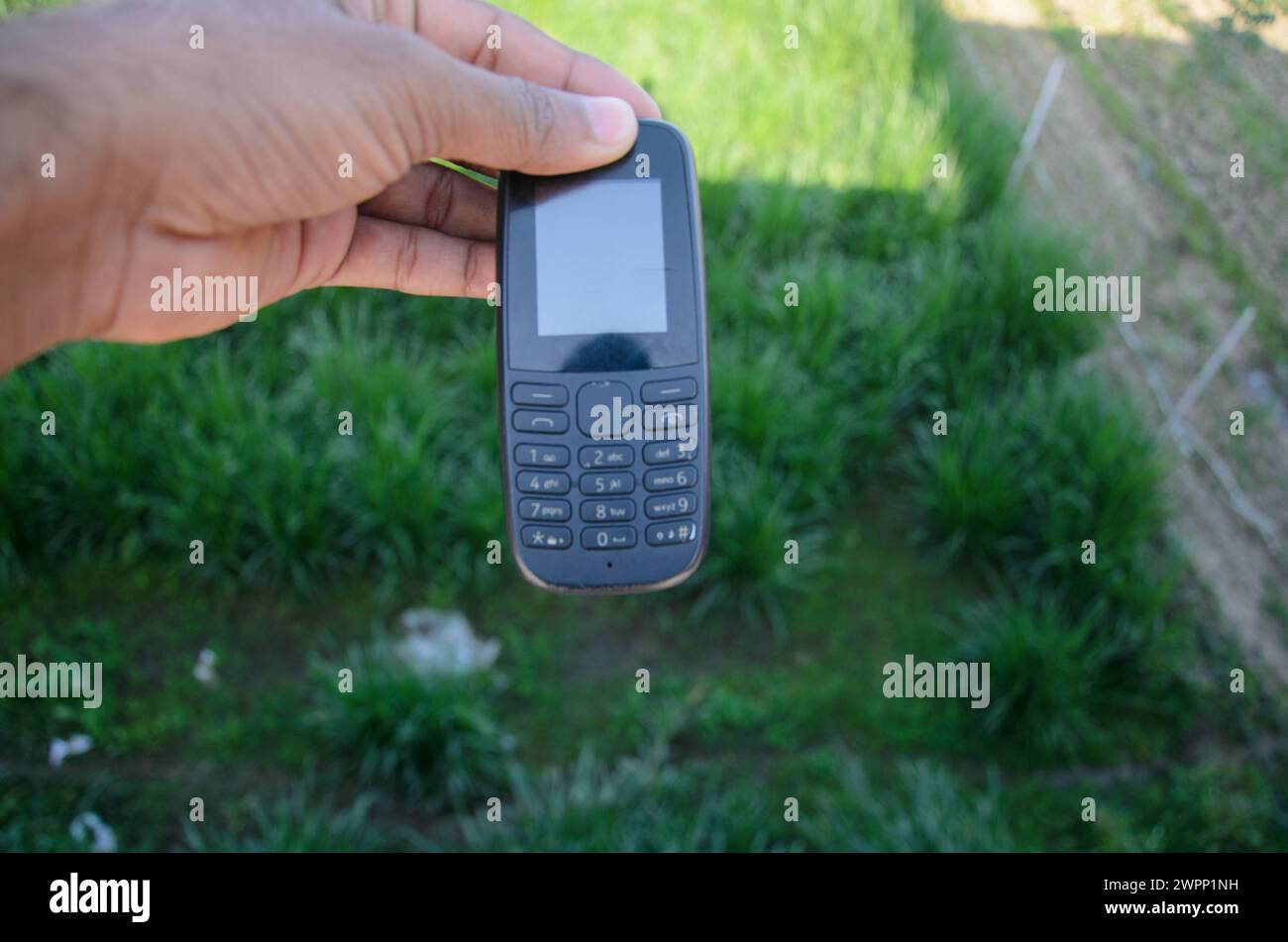 The old keypad phone holding up in hand Stock Photo - Alamy
