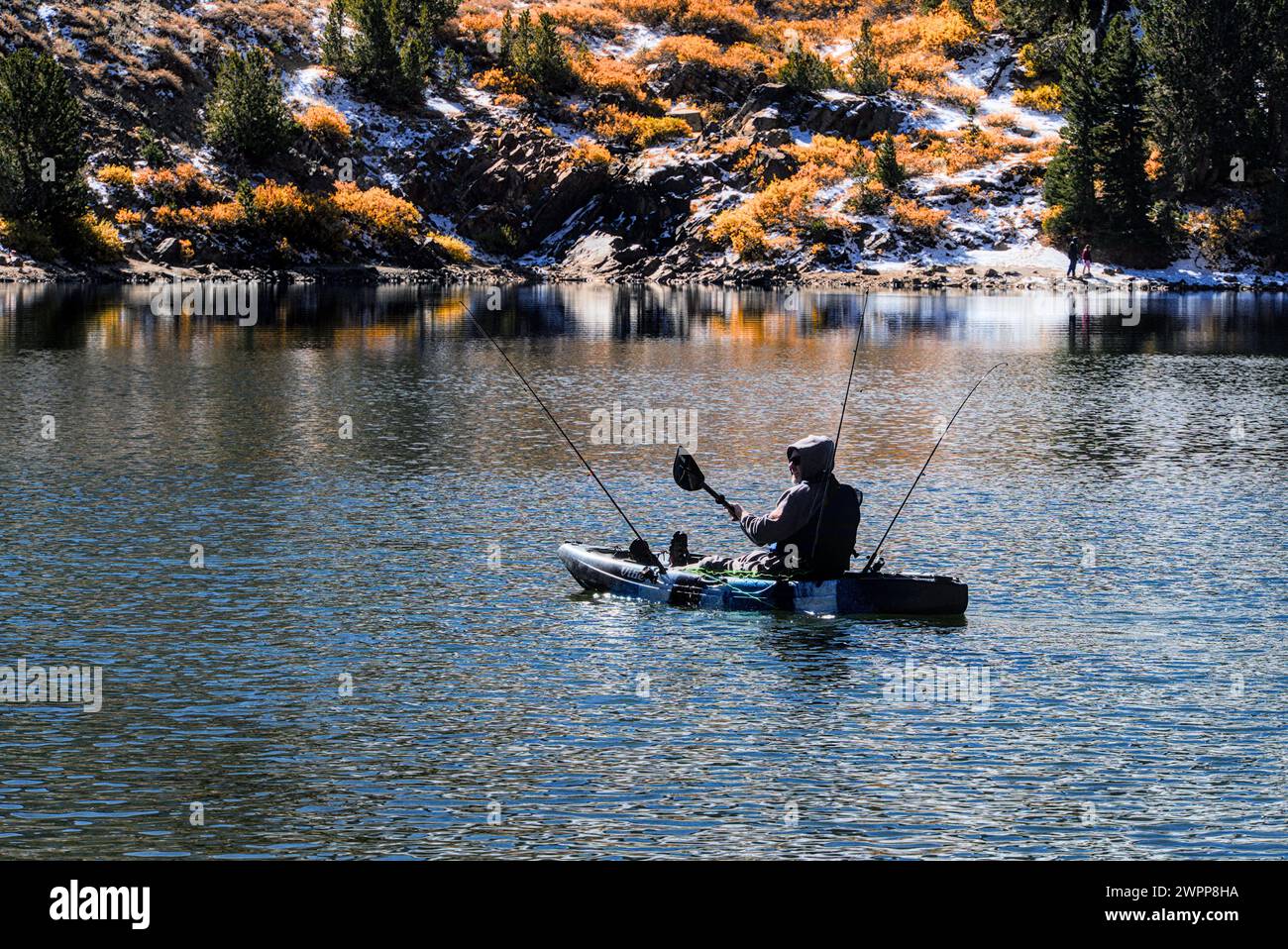 Fishing man on Virginia Lake with changing color trees and snow on the ...