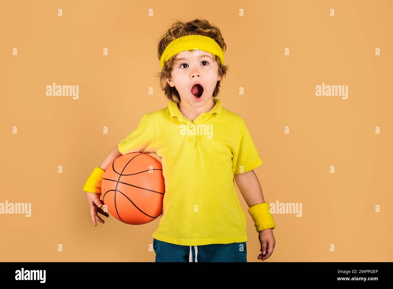 Surprised child boy in sports uniform with basketball ball. Little ...
