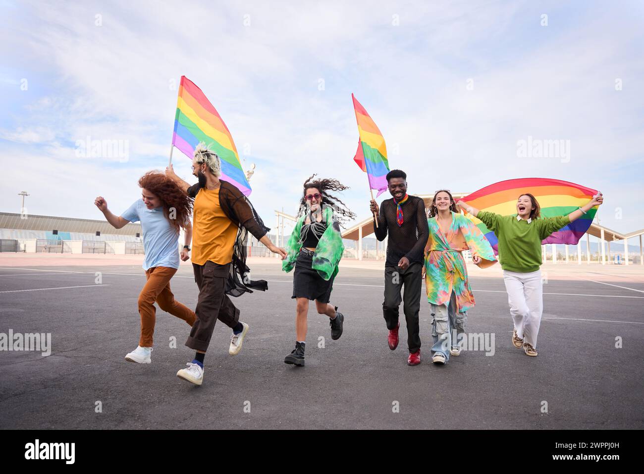 Group happy LGBT people walking down street with rainbow flags under ...