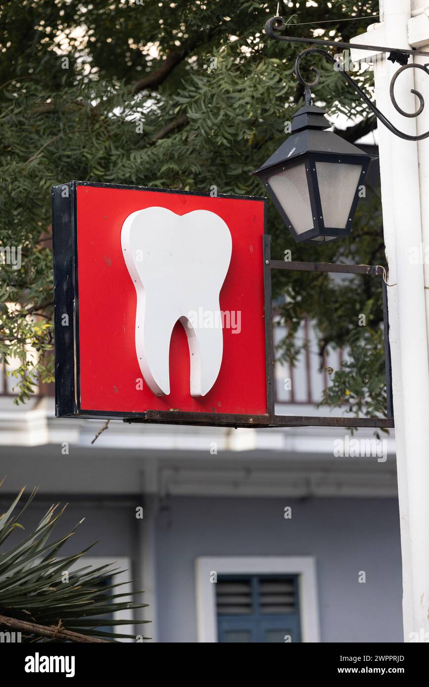 A large white tooth on a red background. An outdoor billboard ...