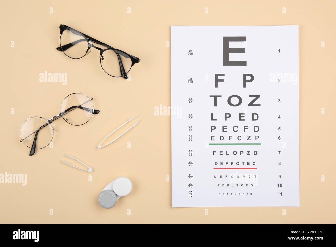 Vision test chart, glasses, lenses and tweezers on beige background ...
