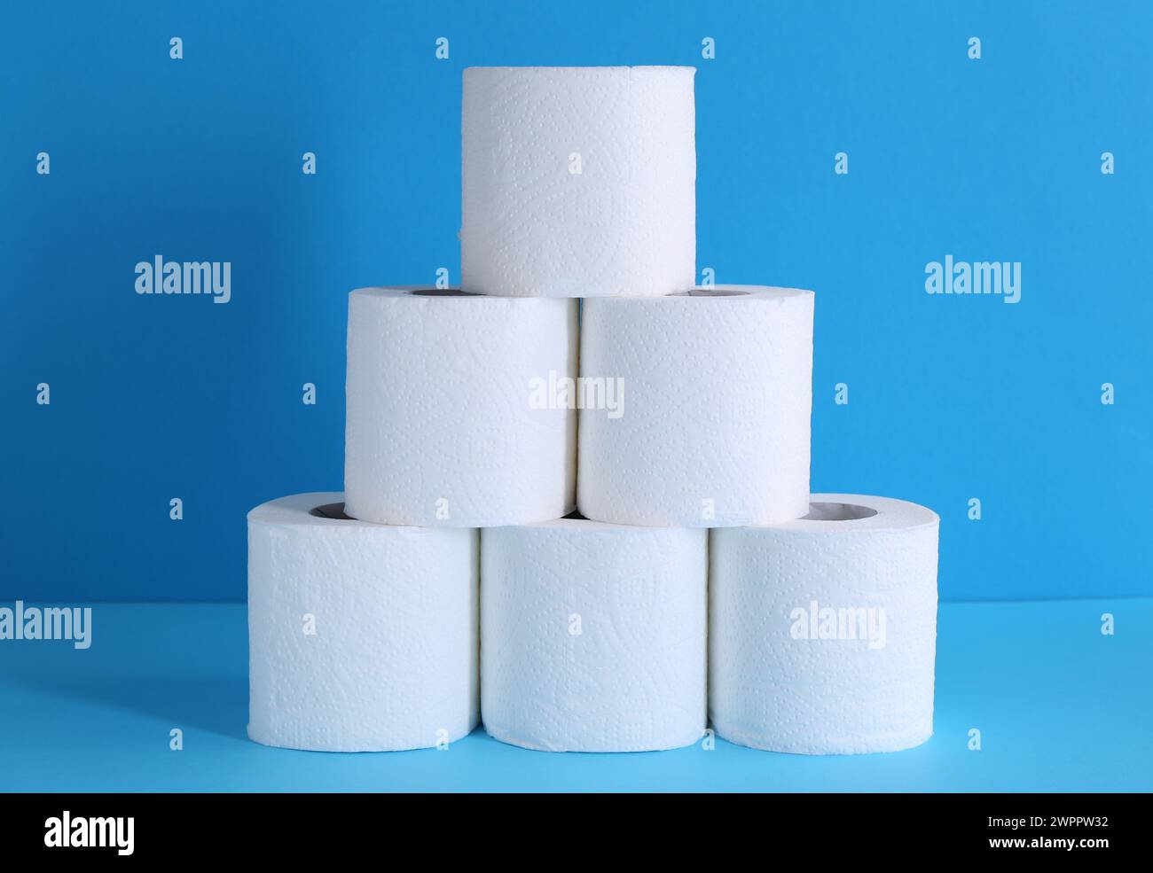 Pyramid of toilet paper rolls on light blue background Stock Photo - Alamy
