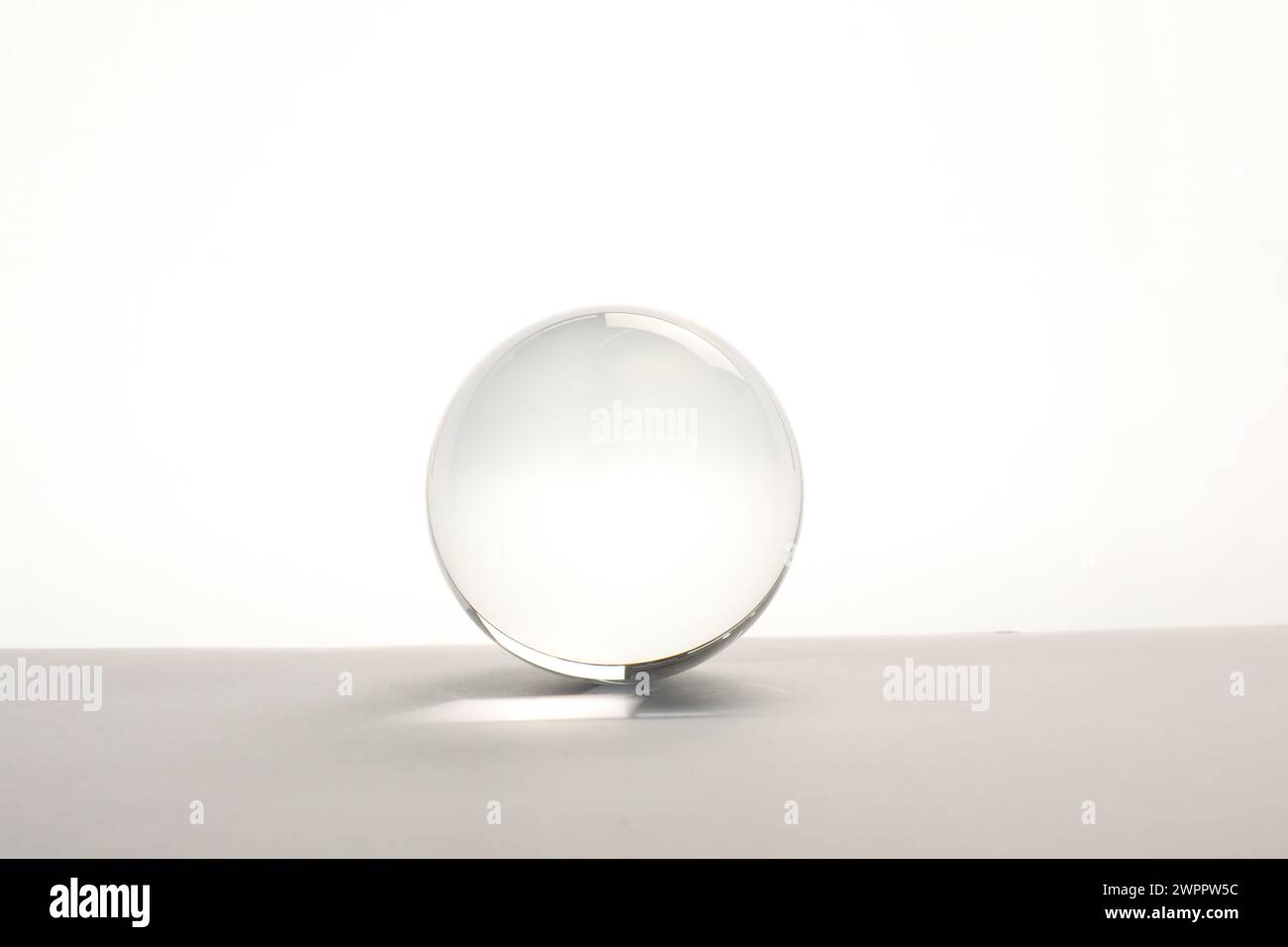 Transparent glass ball on table against white background Stock Photo ...