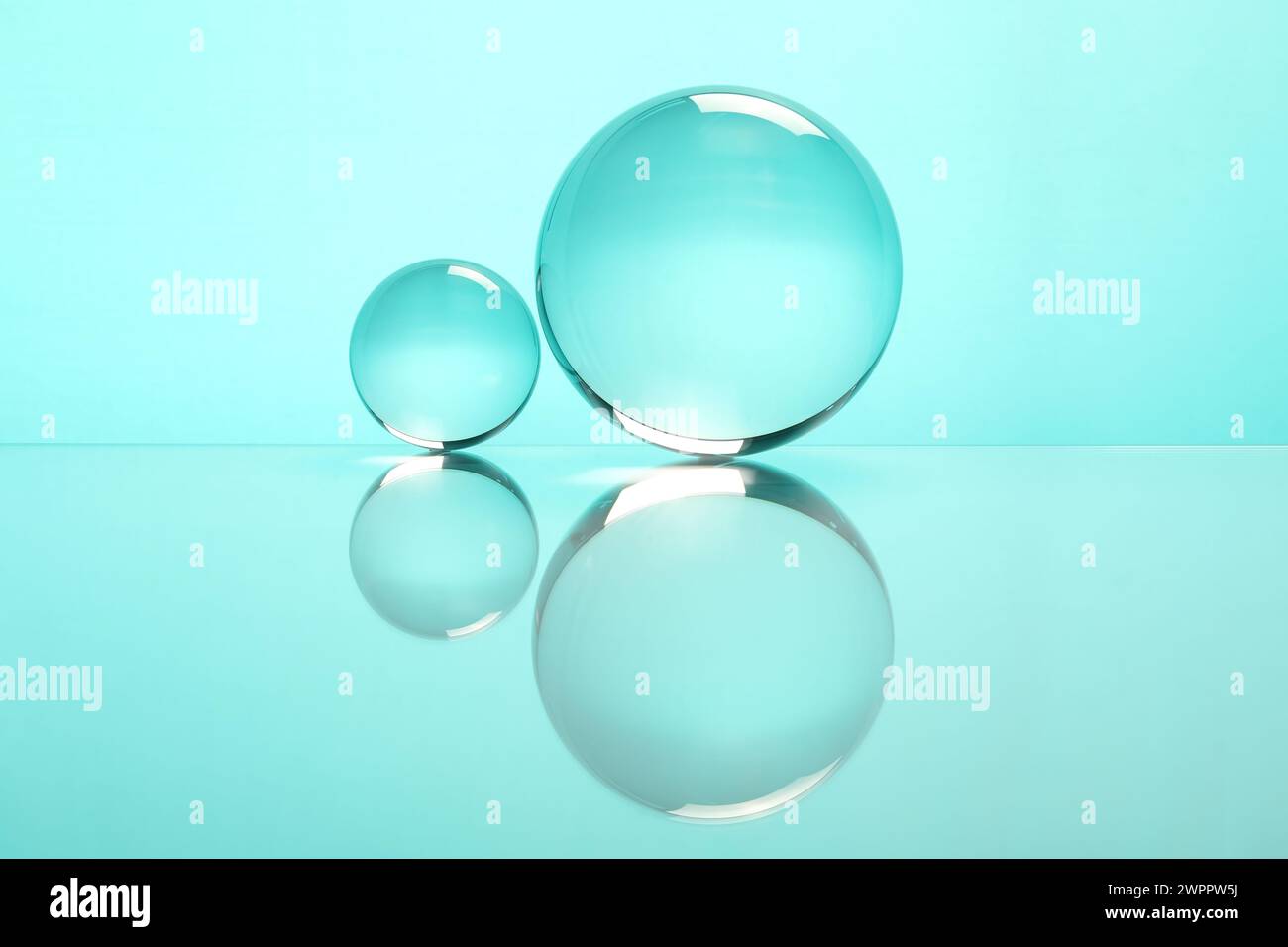 Transparent glass balls on mirror surface against turquoise background ...