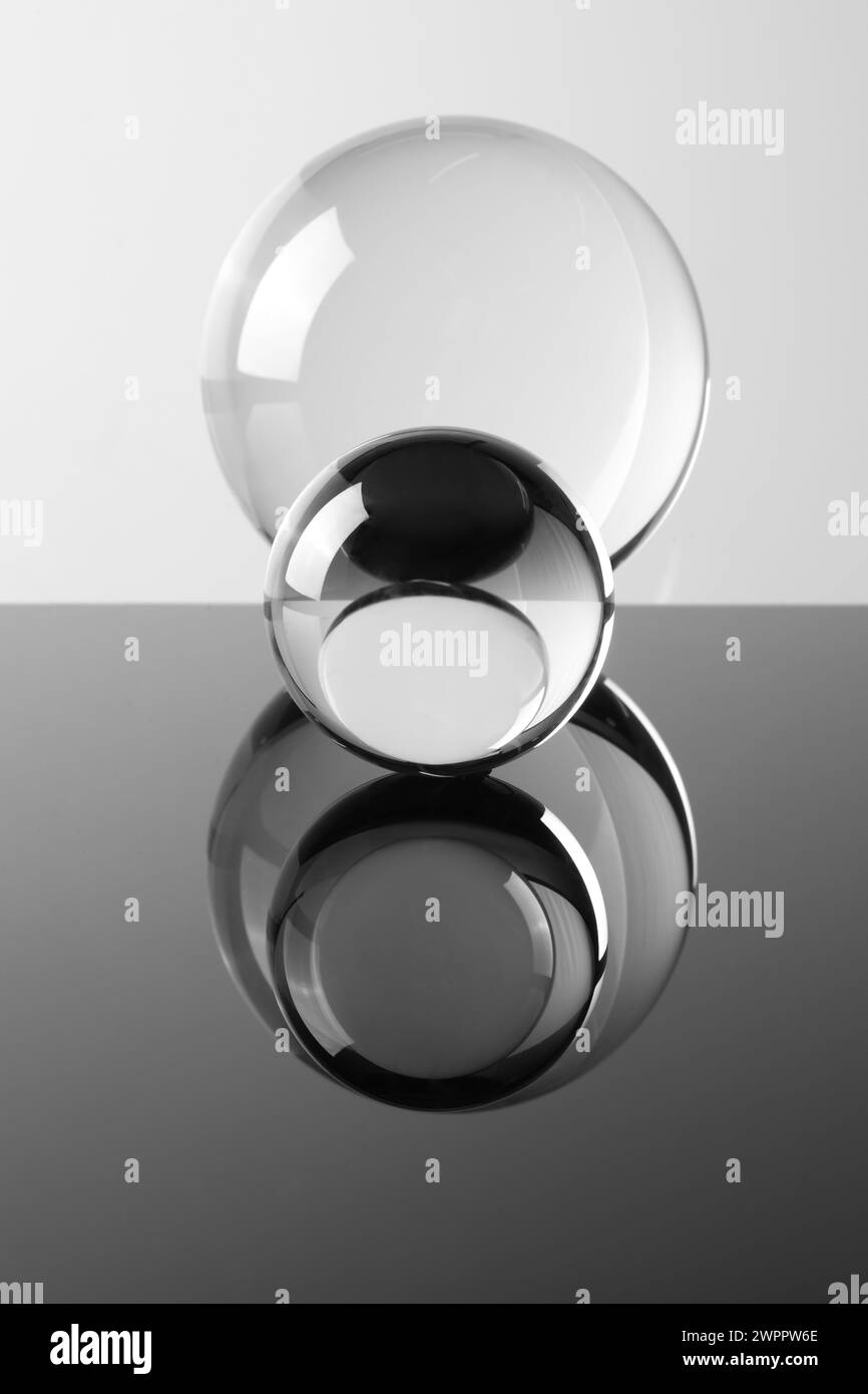 Transparent glass balls on mirror surface against light background ...