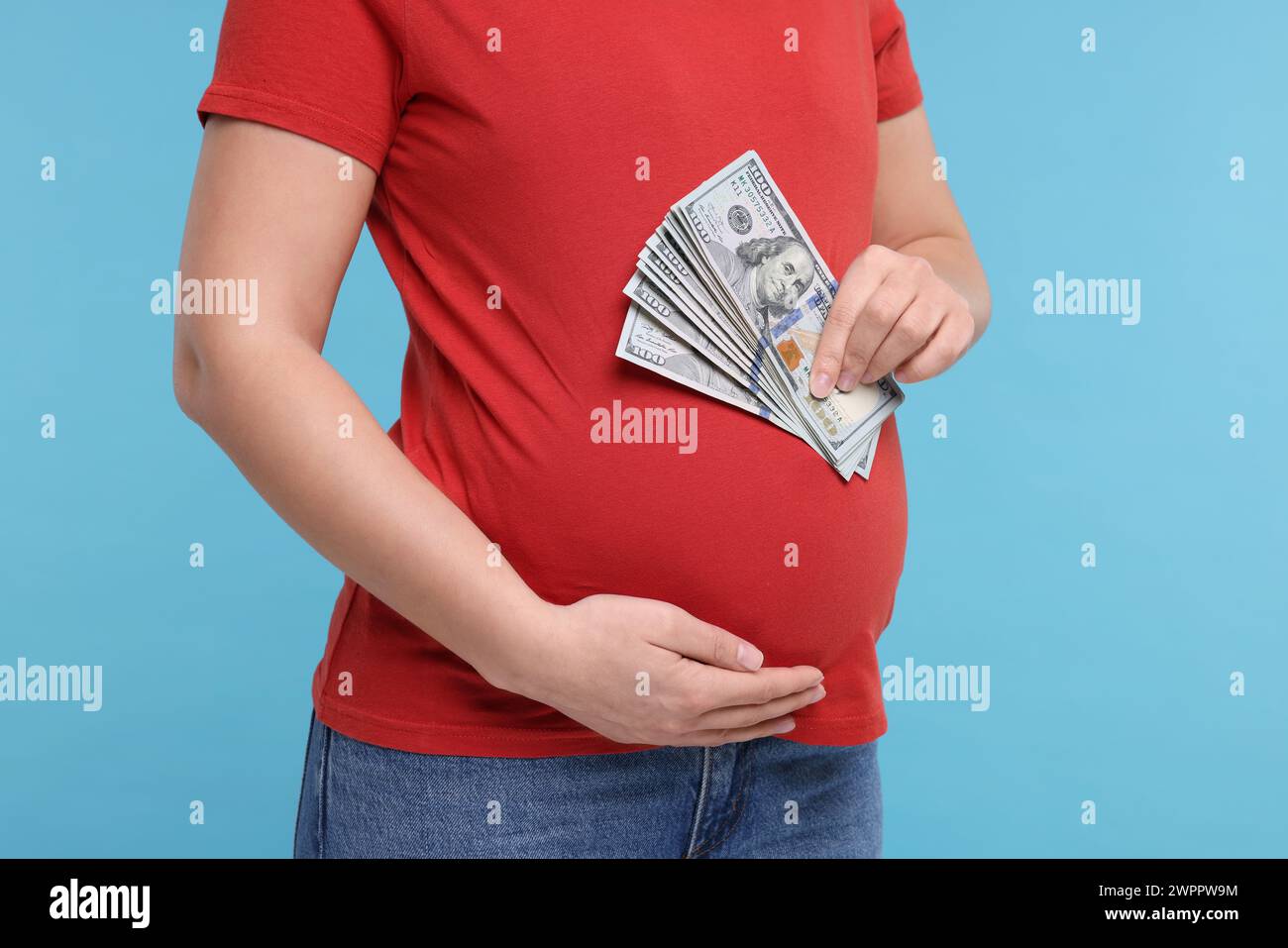 Surrogate mother. Pregnant woman with dollar banknotes on light blue ...
